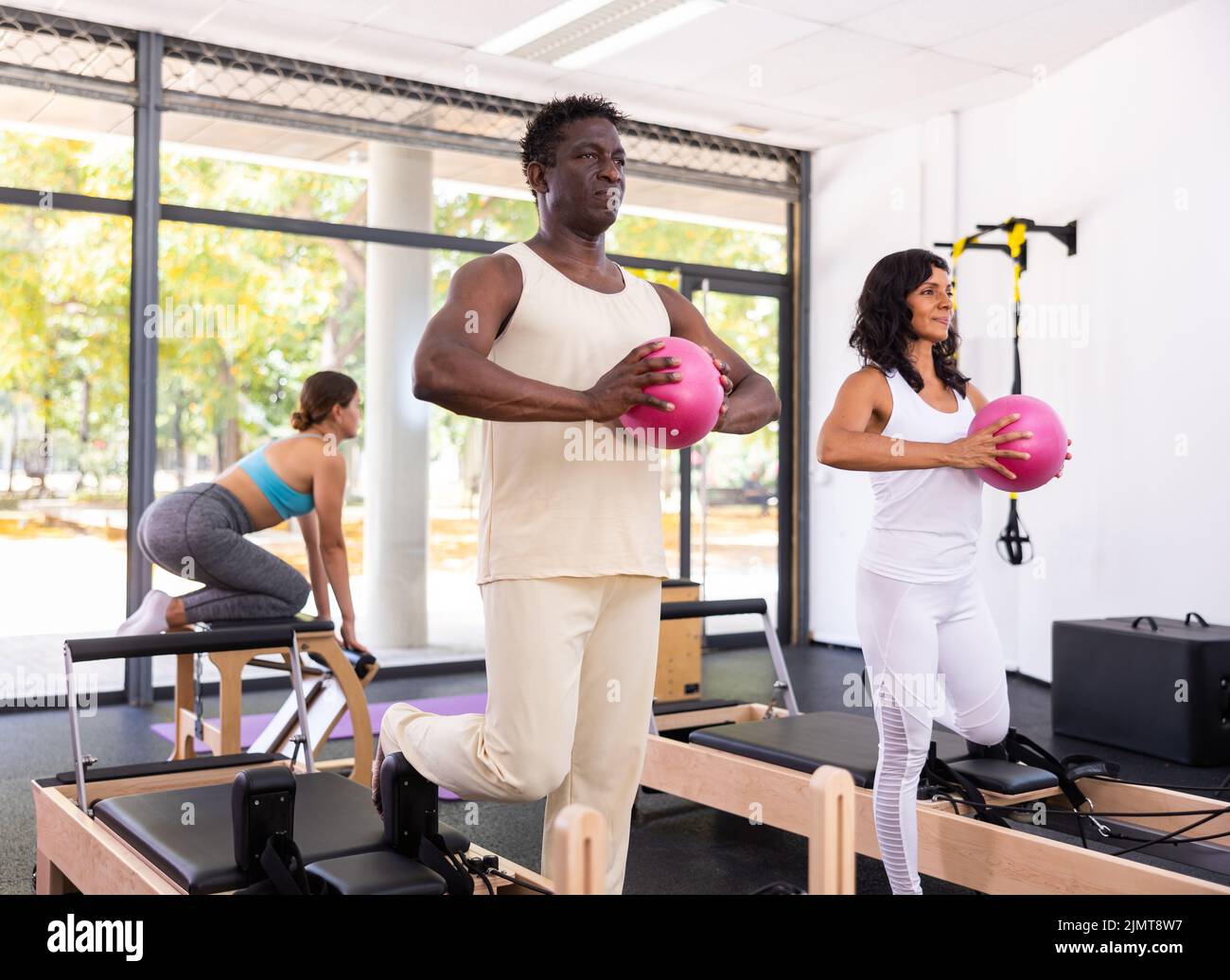 Multiracial group of people doing exercises during pilates training ...
