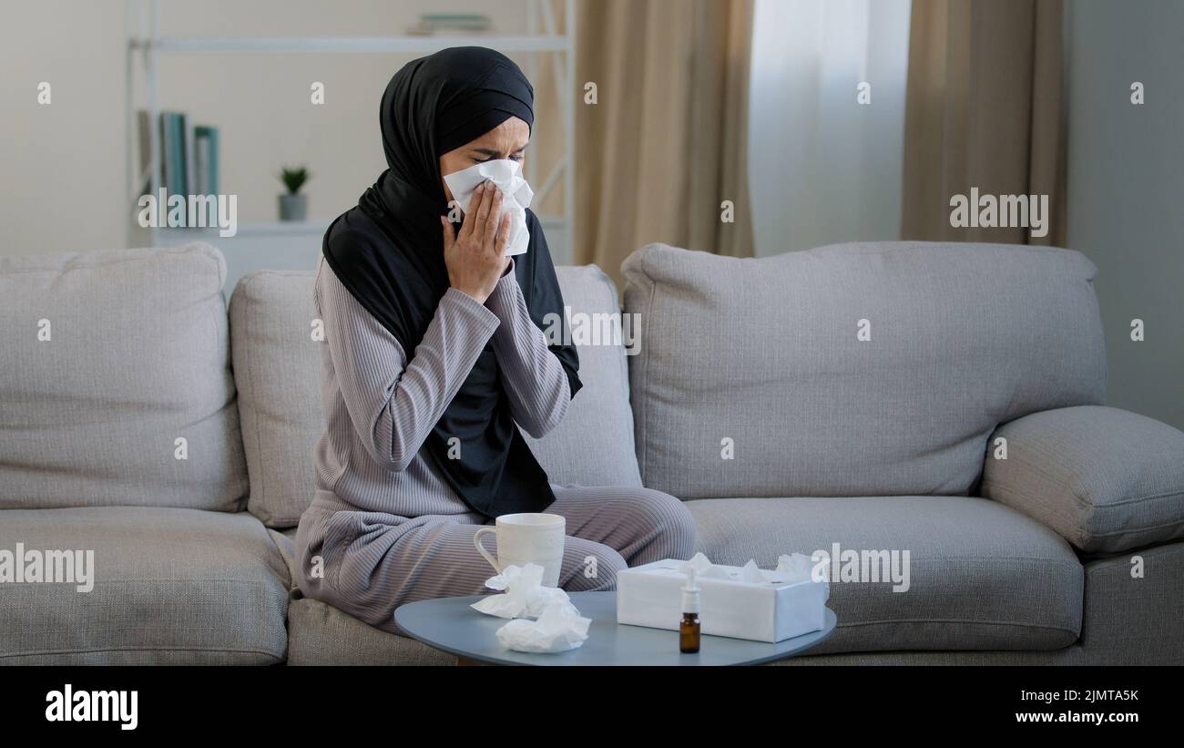 Sick arabian muslim young unhealthy woman in hijab suffer from runny nose flu disease seasonal ...