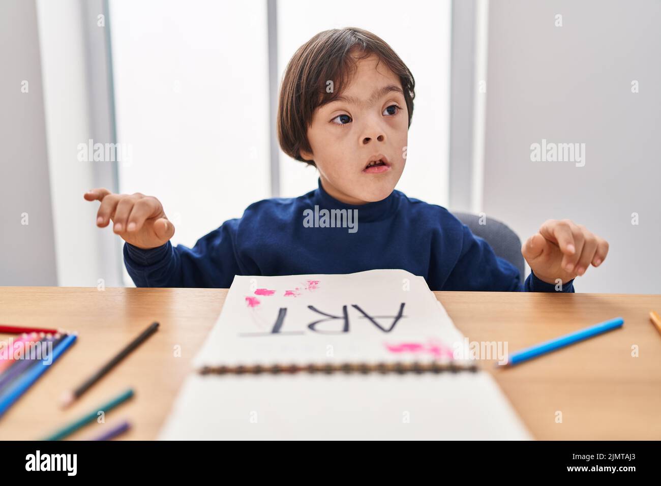 Down syndrome kid drawing on notebook at school Stock Photo - Alamy