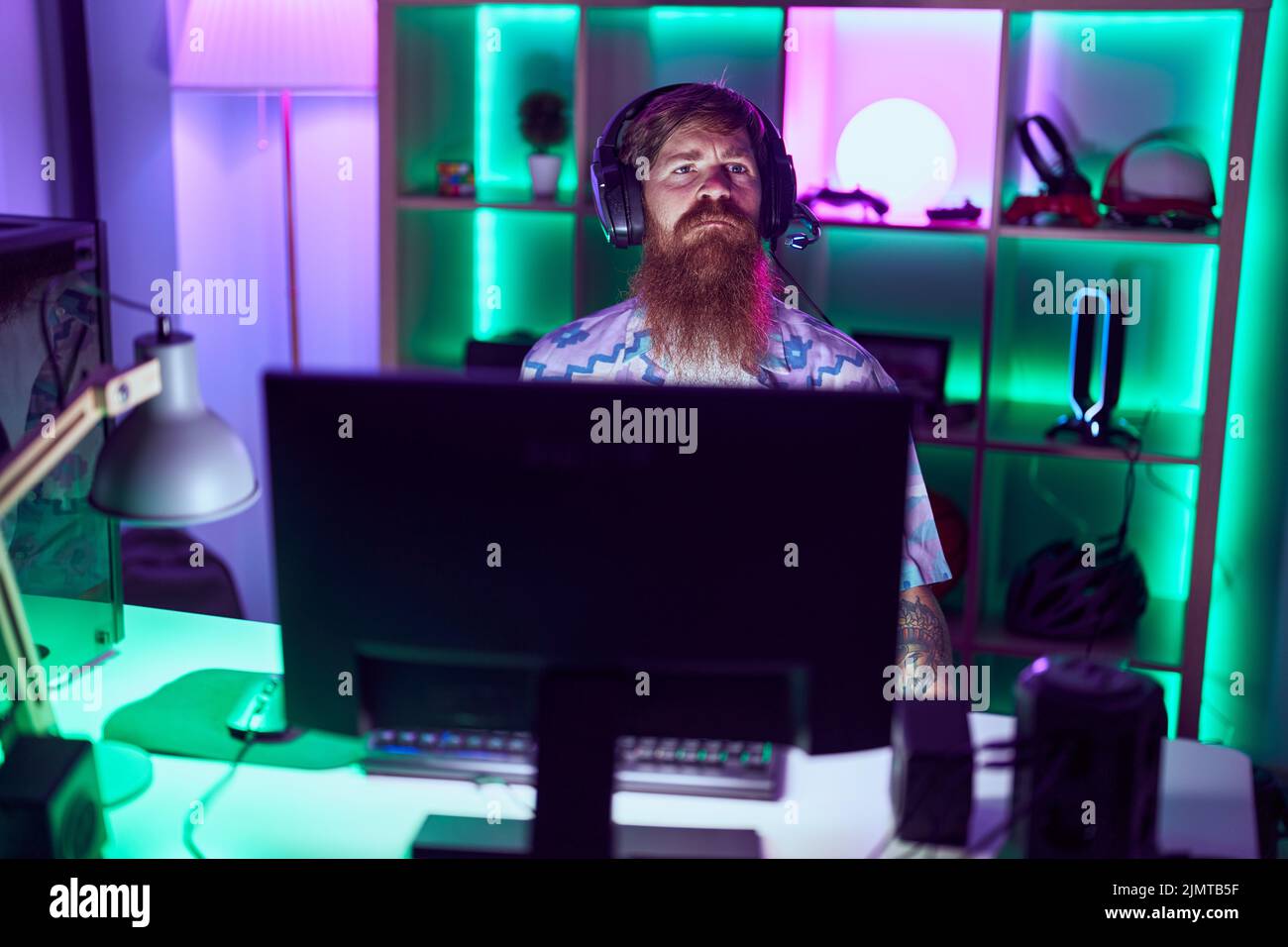 Young redhead man streamer playing video game using computer at gaming ...
