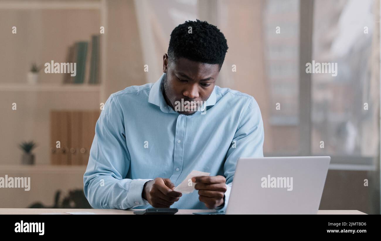 Young African focused man bank employee bookkeeper hold payment bill ...