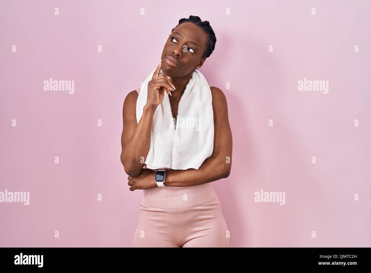 Beautiful black woman wearing sportswear and towel over pink background ...