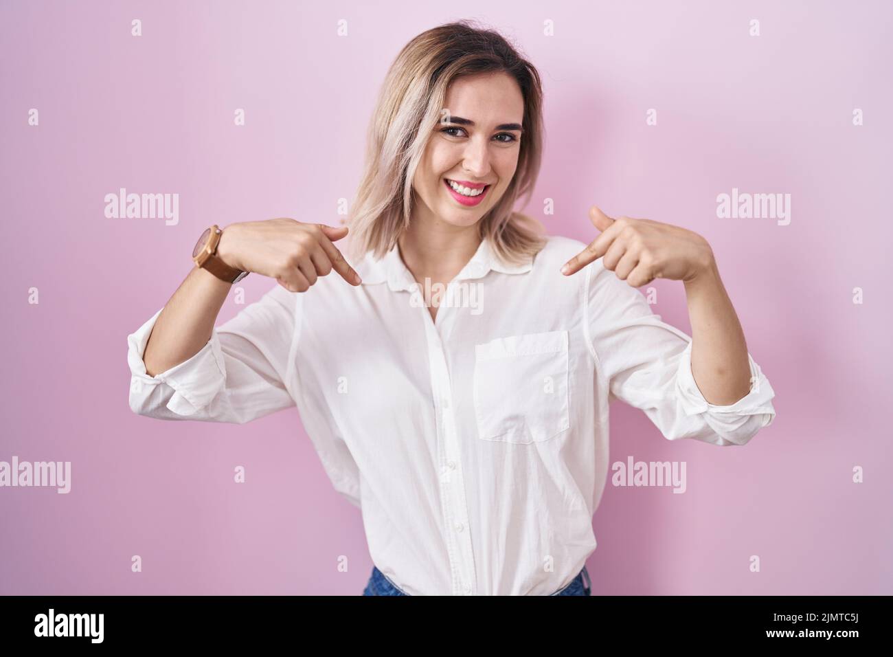 Young beautiful woman standing over pink background looking confident ...