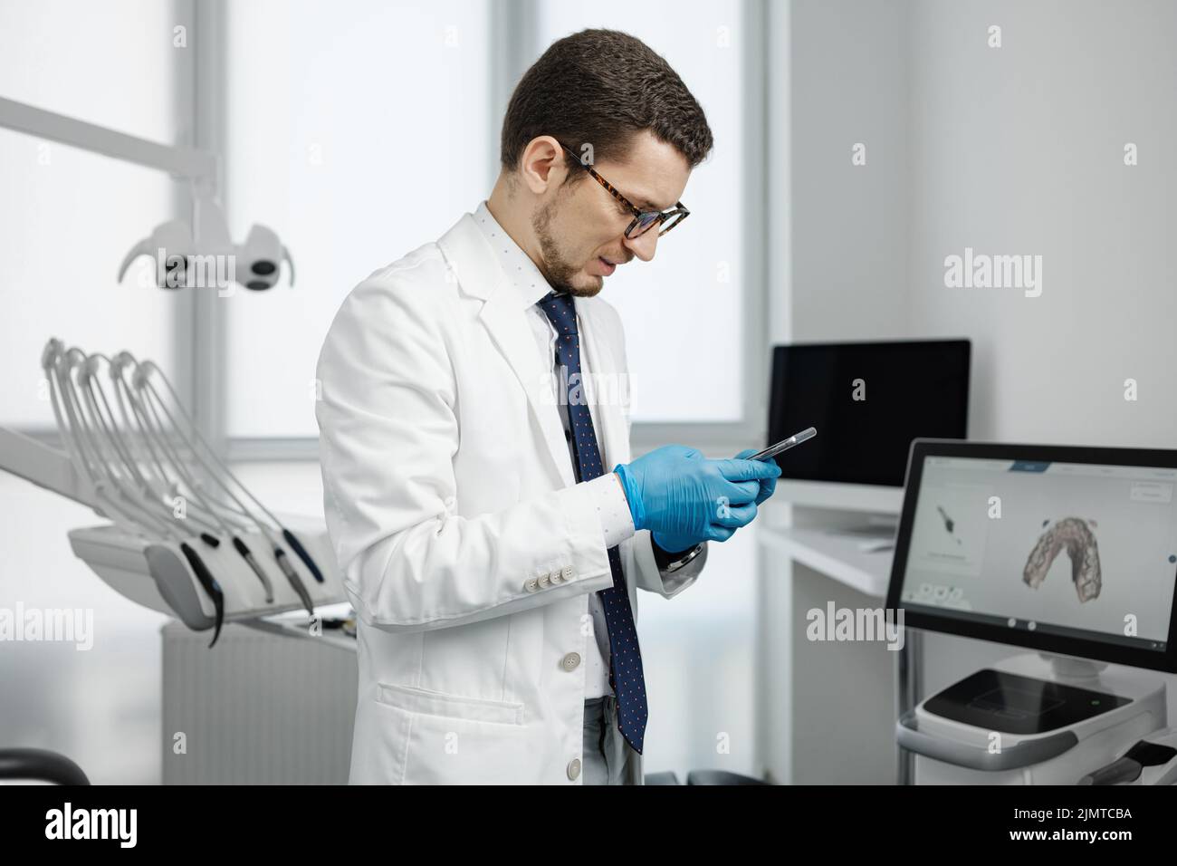 Handsome male dentist using smartphone in dental office Stock Photo - Alamy