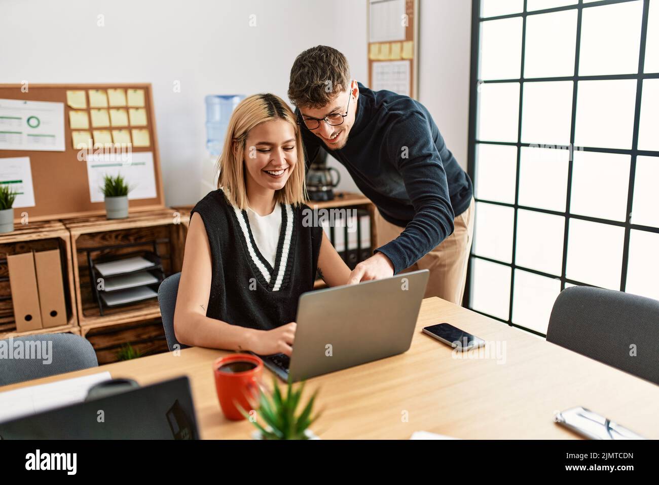 Two business workers smiling happy working using laptop at the office ...