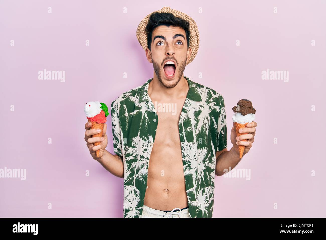 Young hispanic man wearing summer style holding ice cream angry and mad ...