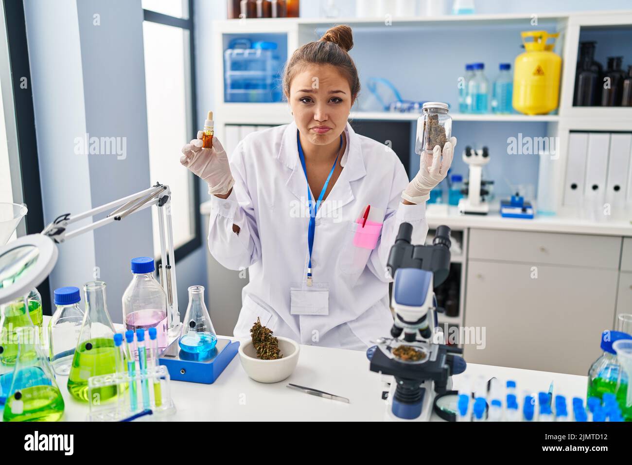 Young hispanic woman doing weed oil extraction at laboratory depressed ...