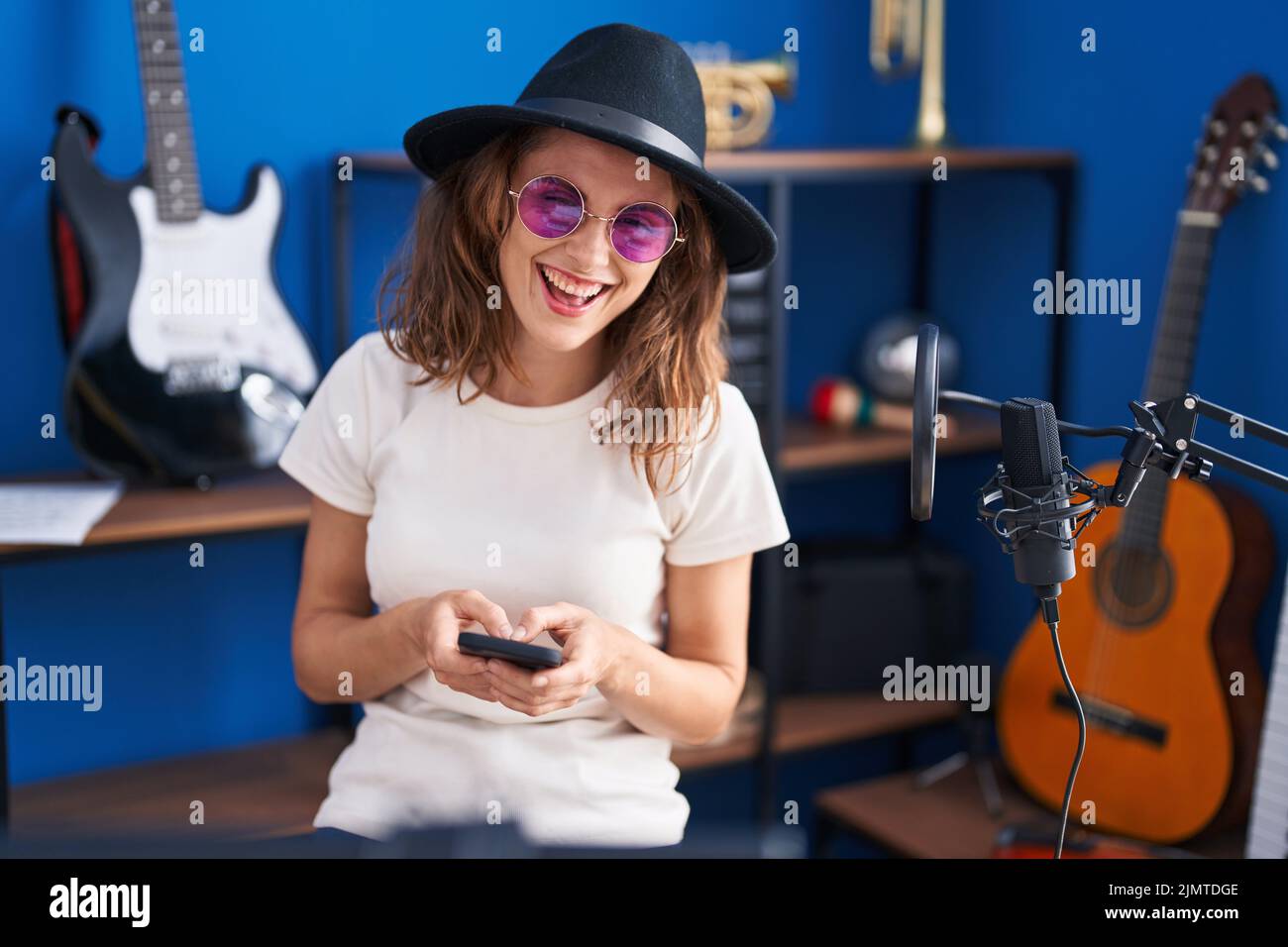 Young woman musician smiling confident using smartphone at music studio ...