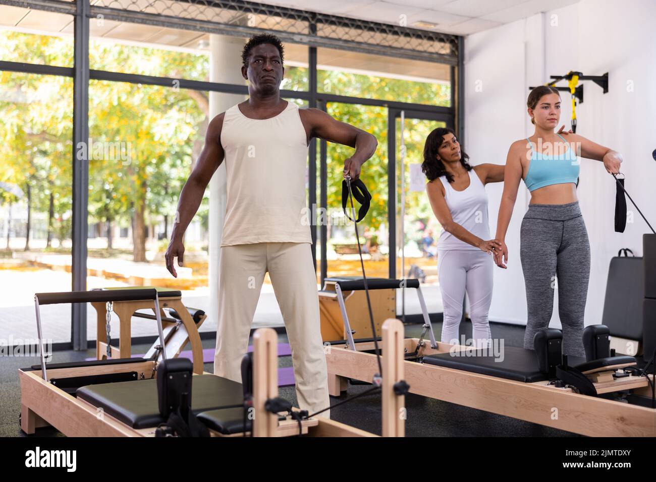 Man stretching body on pilates chair while doing forward bends during ...