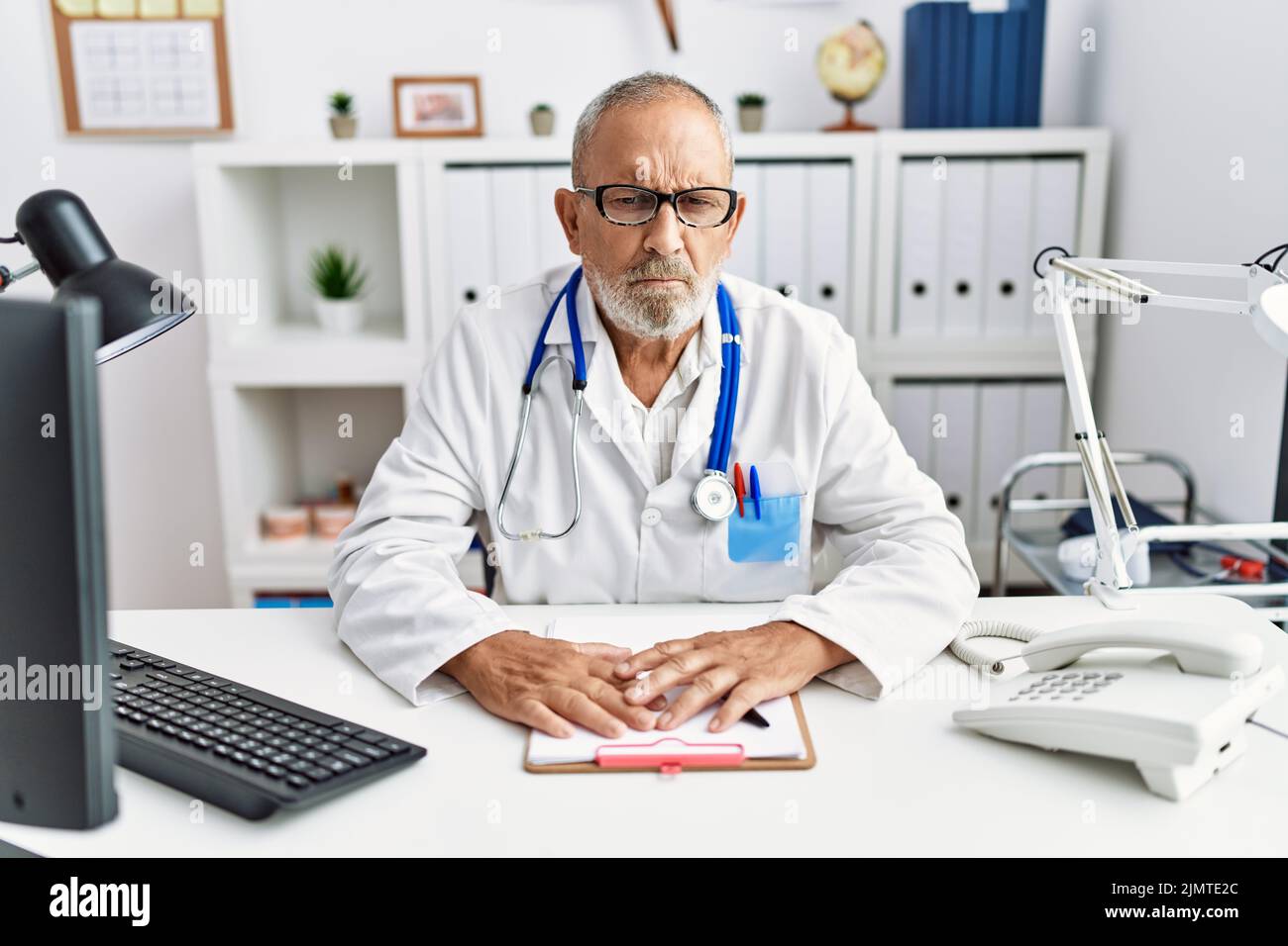 Mature doctor man at the clinic skeptic and nervous, frowning upset ...