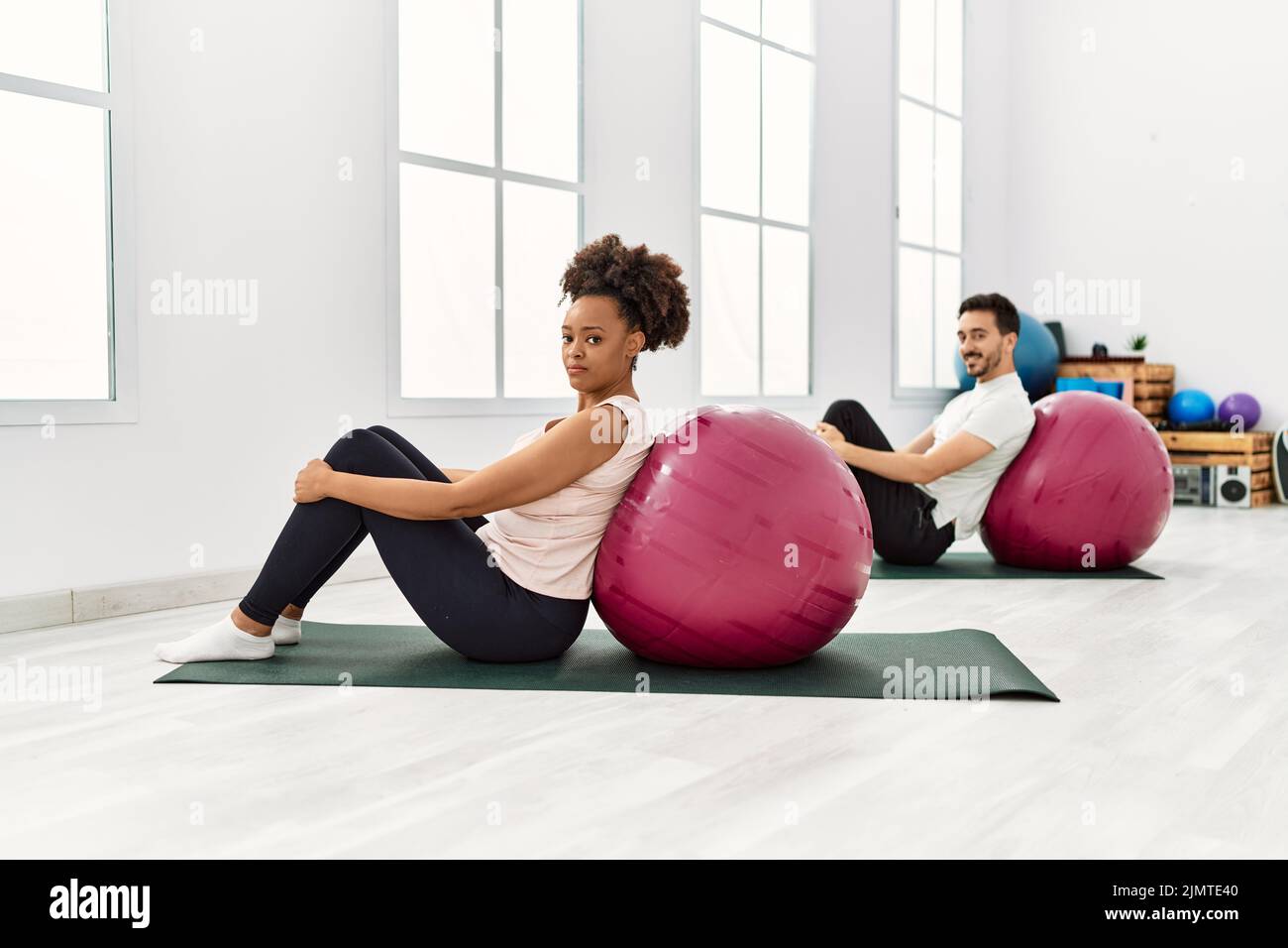 Young african american woman and hispanic man exercising at pilates ...