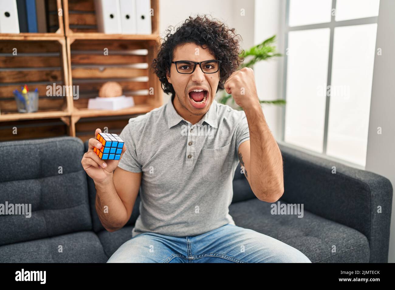Hispanic man with curly hair playing colorful puzzle cube intelligence ...