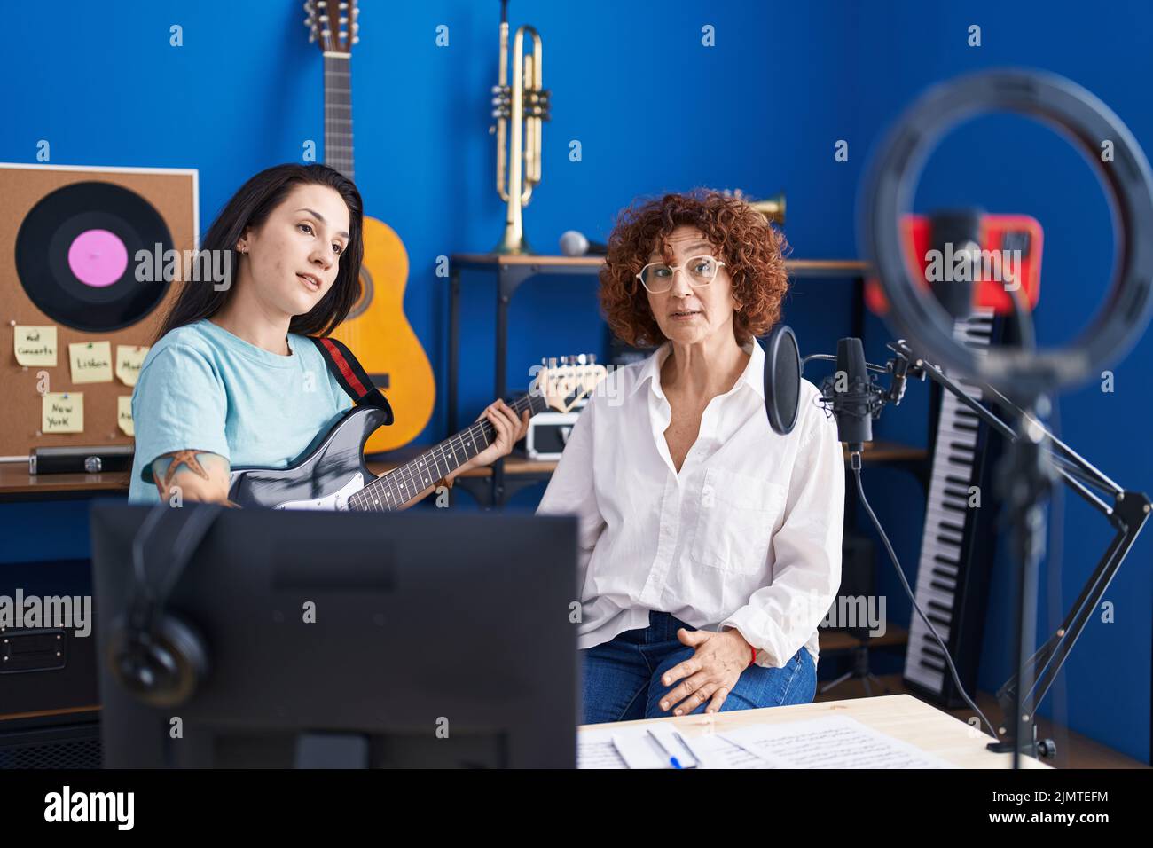 Two women musicians having online electrical guitar lesson by ...