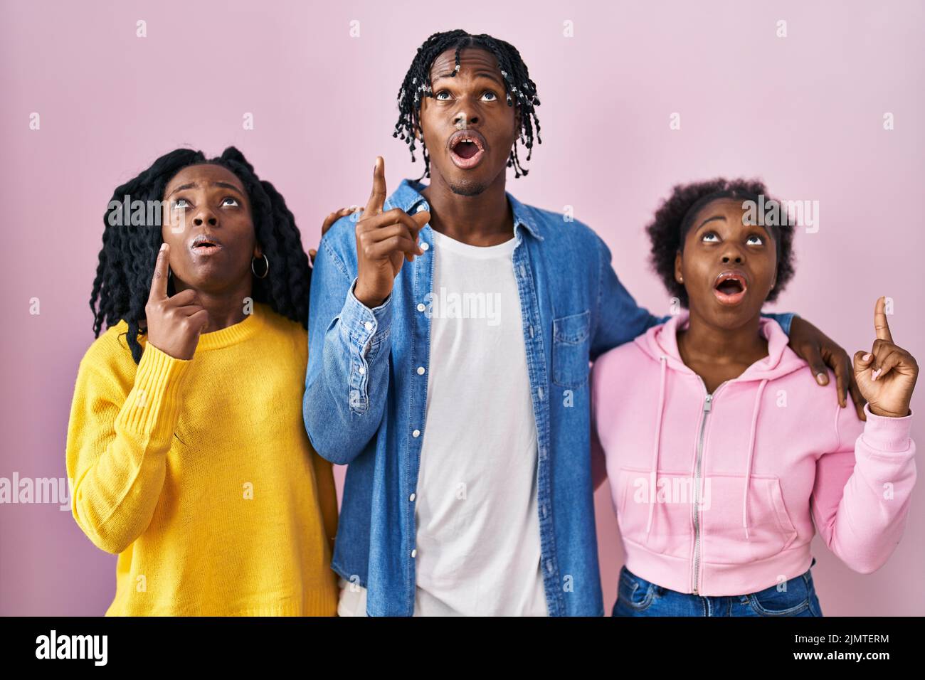 Group of three young black people standing together over pink ...