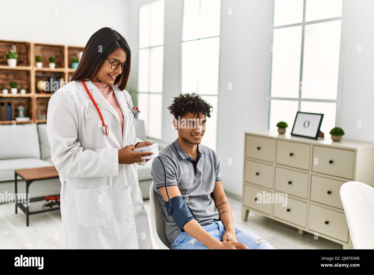 Young latin doctor woman smiling happy measuring pulse using ...