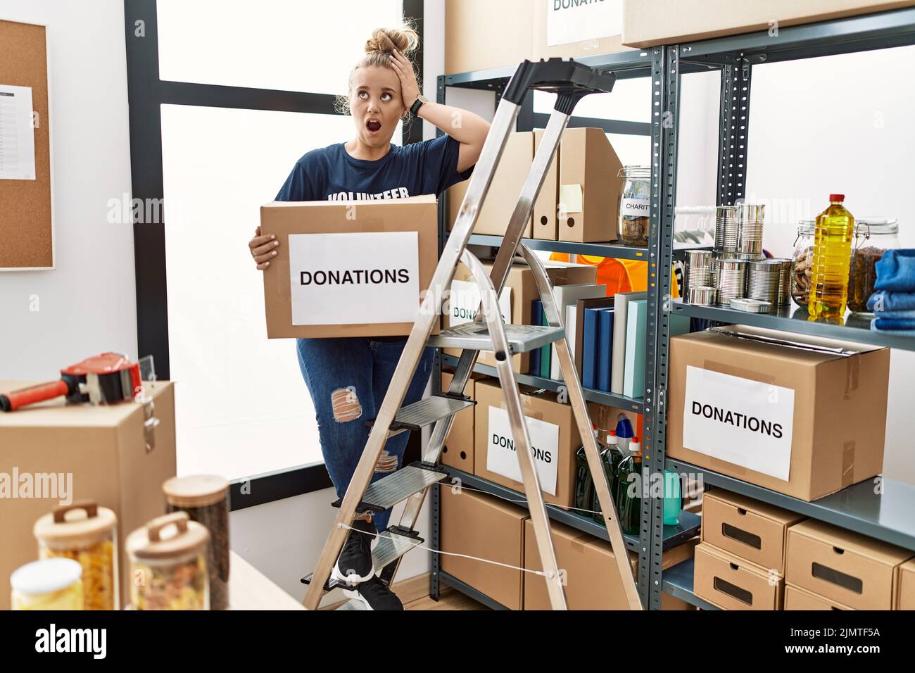 Young caucasian woman volunteer holding donations box crazy and scared ...