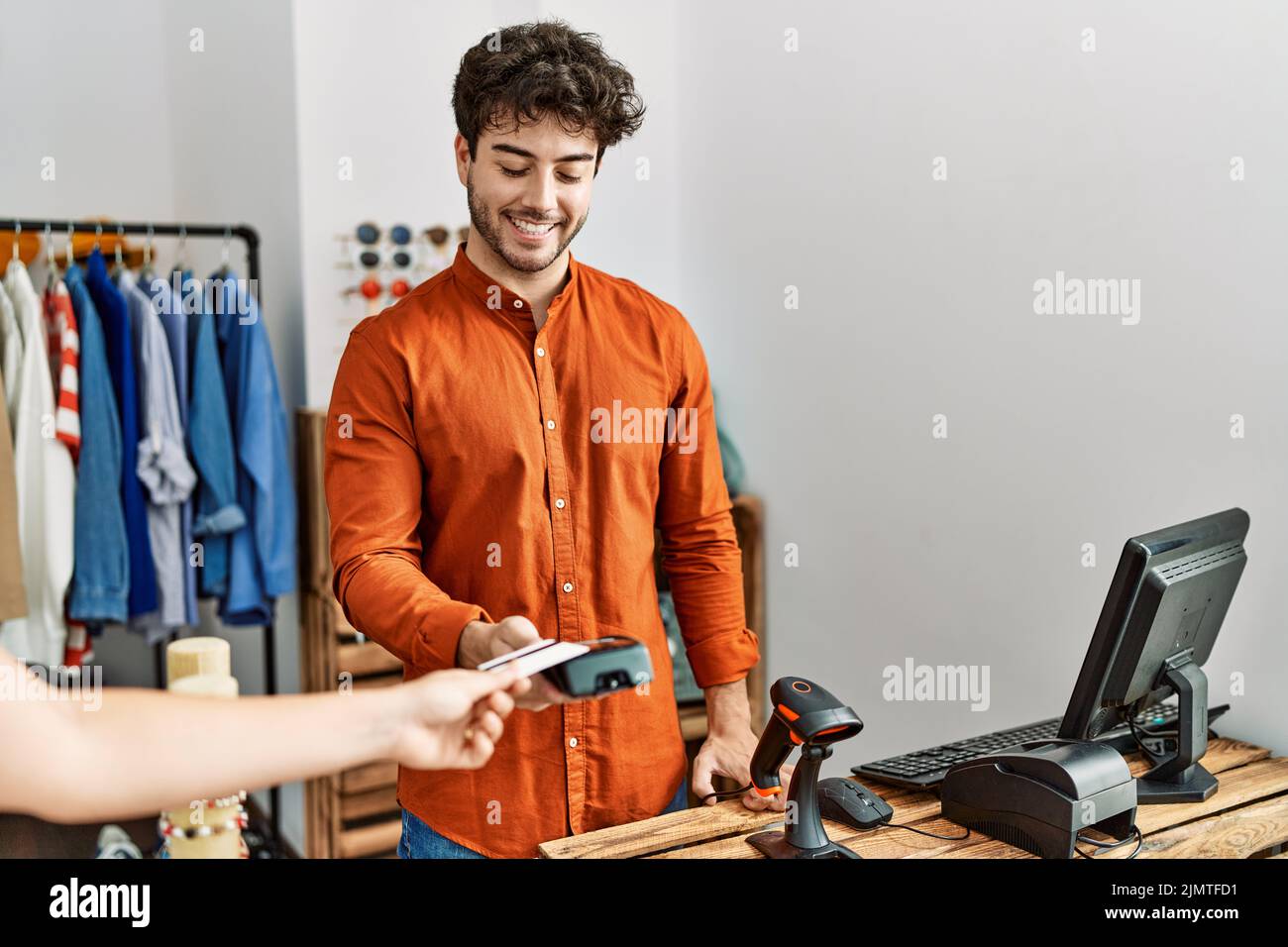 Customer hand paying to shopkeeper man using credit card at clothing ...