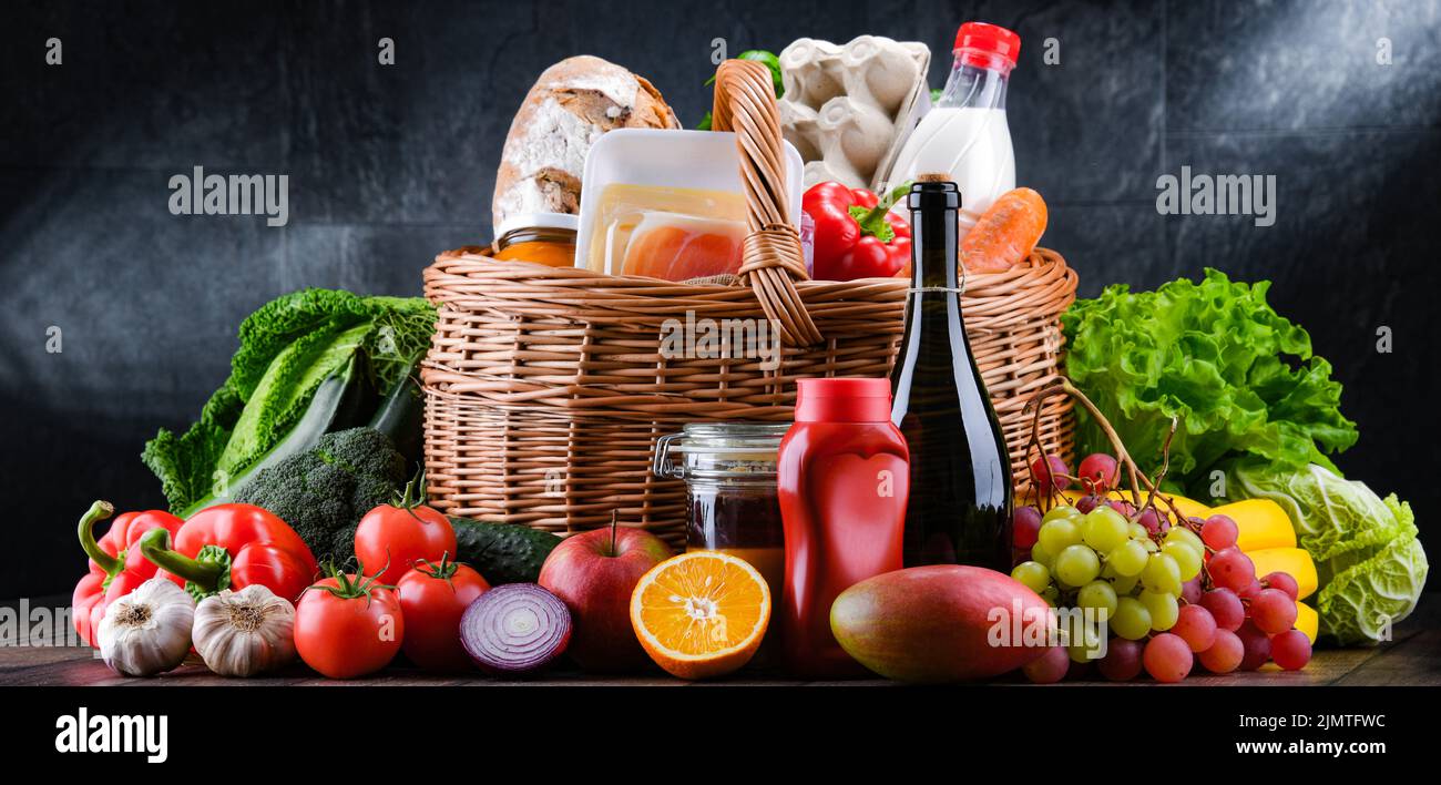 Wicker basket with assorted grocery products including fresh vegetables ...