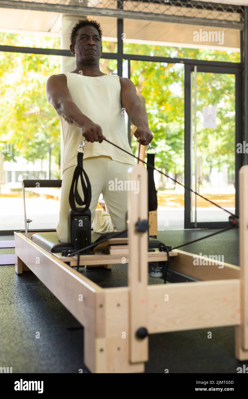 Man stretching on pilates reformer in gym Stock Photo - Alamy