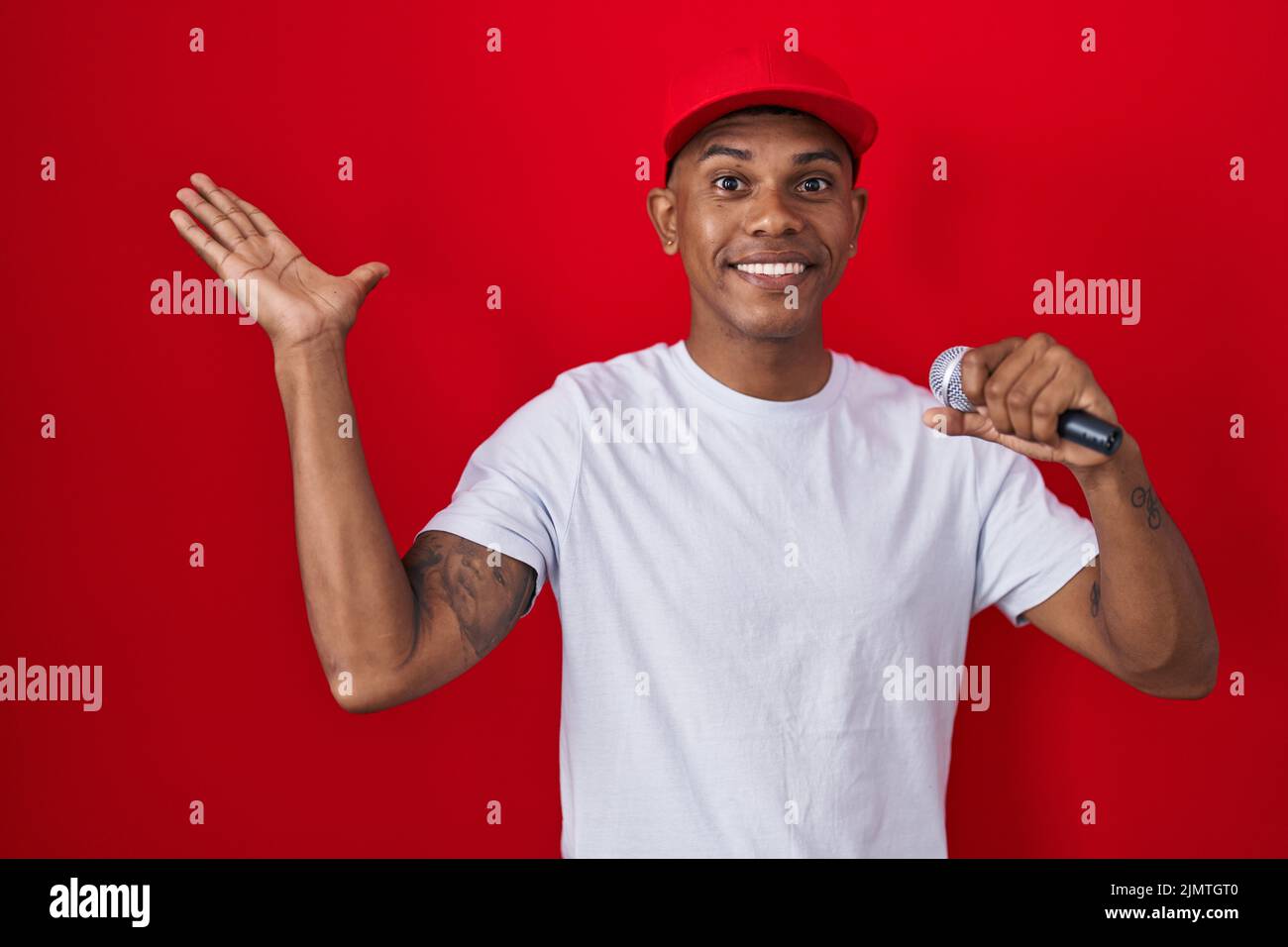 Young hispanic man singing song using microphone celebrating victory ...