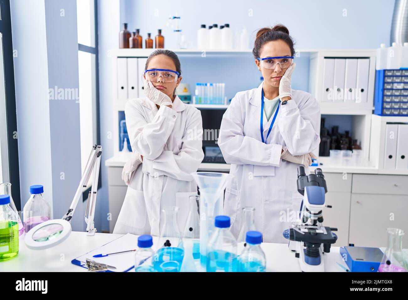 Young mother and daughter at scientist laboratory thinking looking ...
