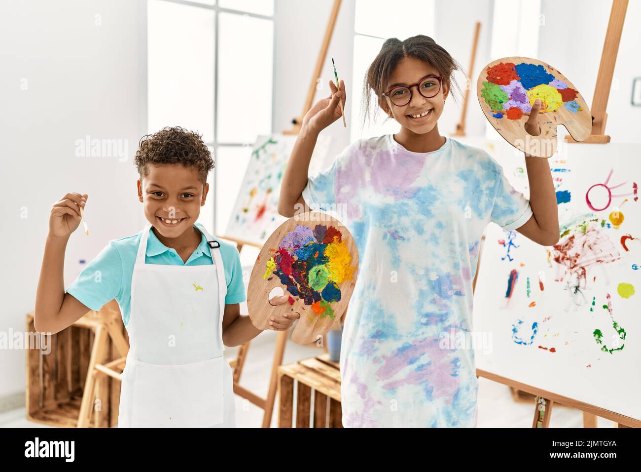 Brother and sister smiling confident holding paintbrush and palette at ...