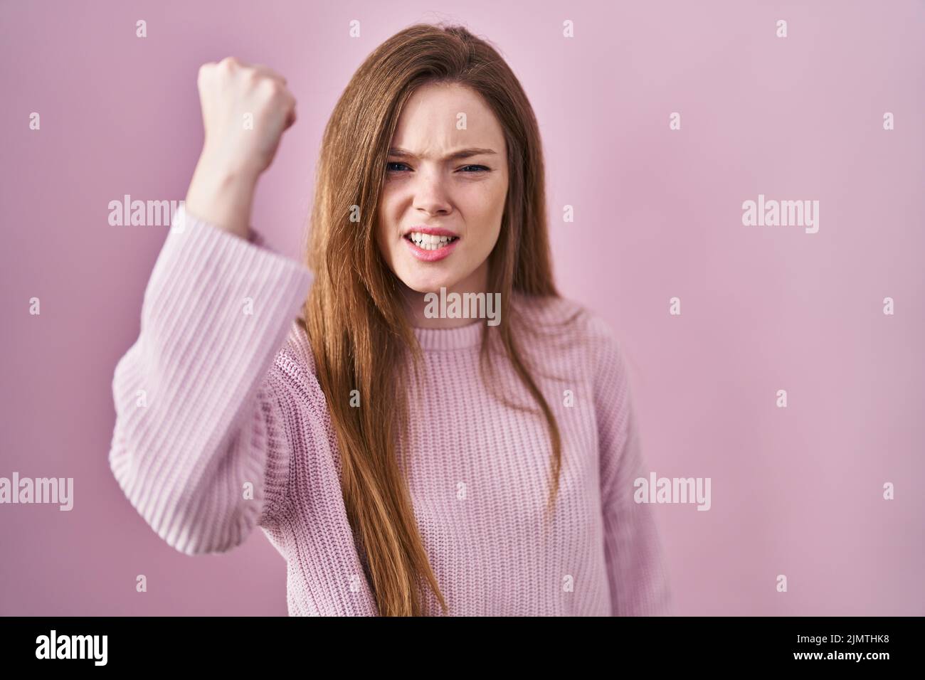 Young caucasian woman standing over pink background angry and mad ...