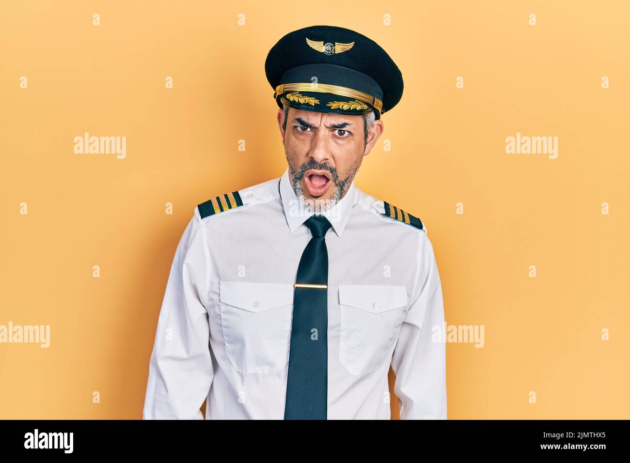 Handsome middle age man with grey hair wearing airplane pilot uniform ...