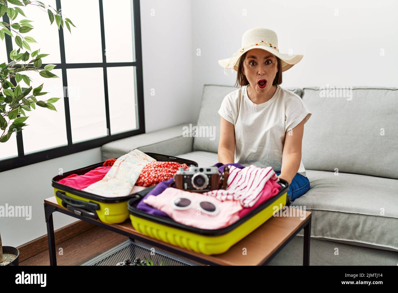 Beautiful middle age hispanic woman packing summer clothes in suitcase ...