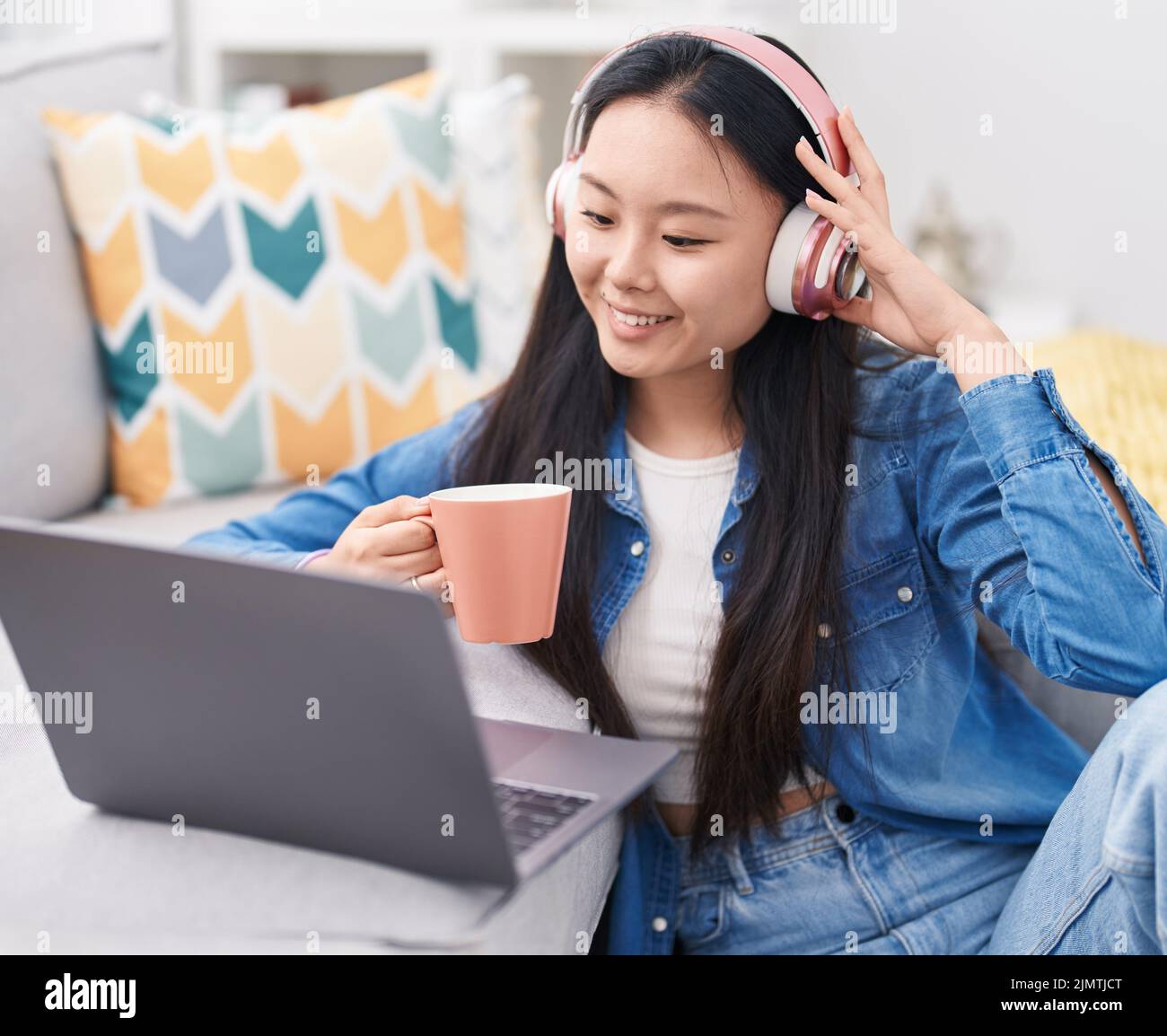Young chinese woman listening to music drinking coffee at home Stock ...