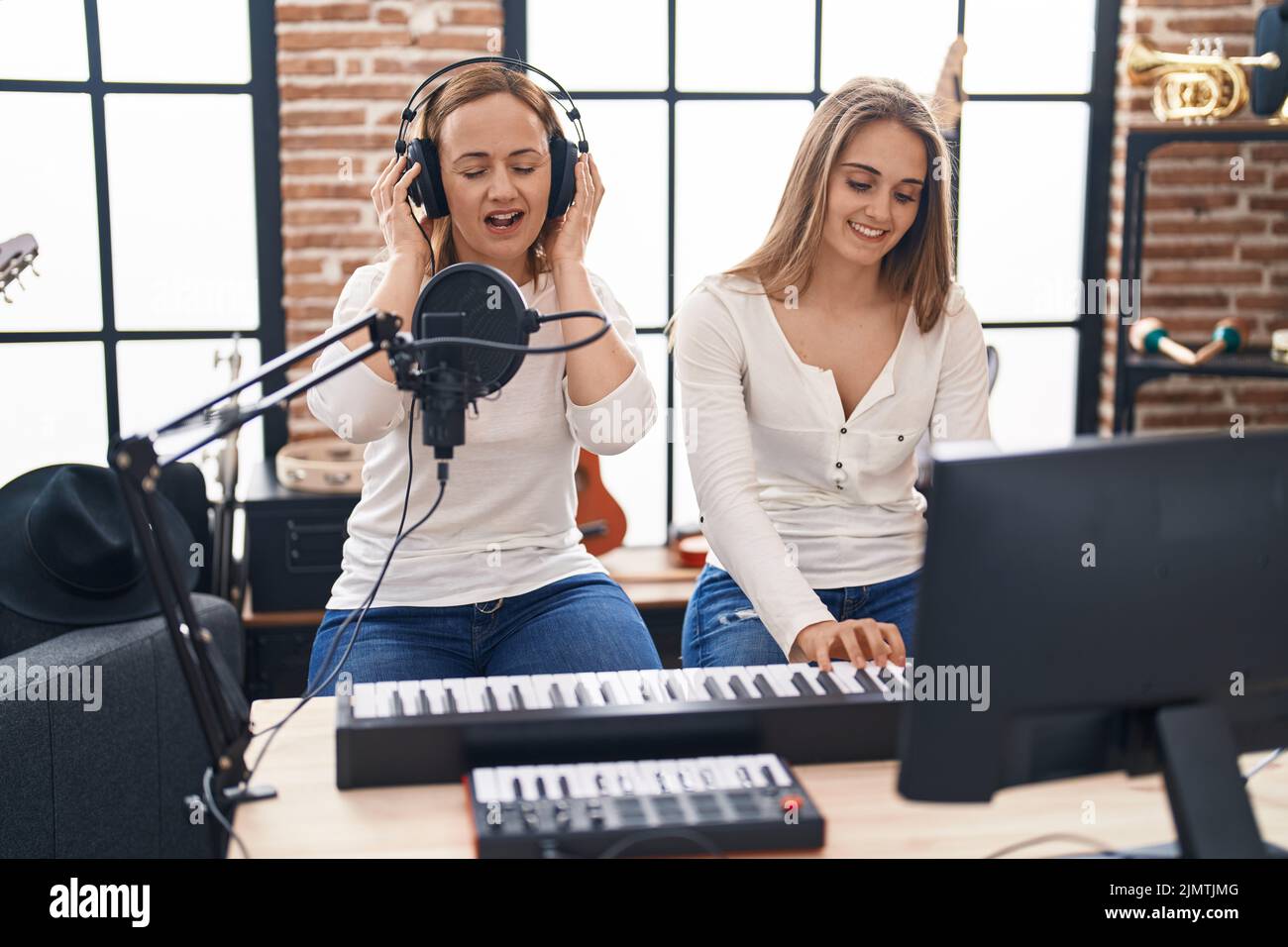 Two women musicians singing song playing piano at music studio Stock ...