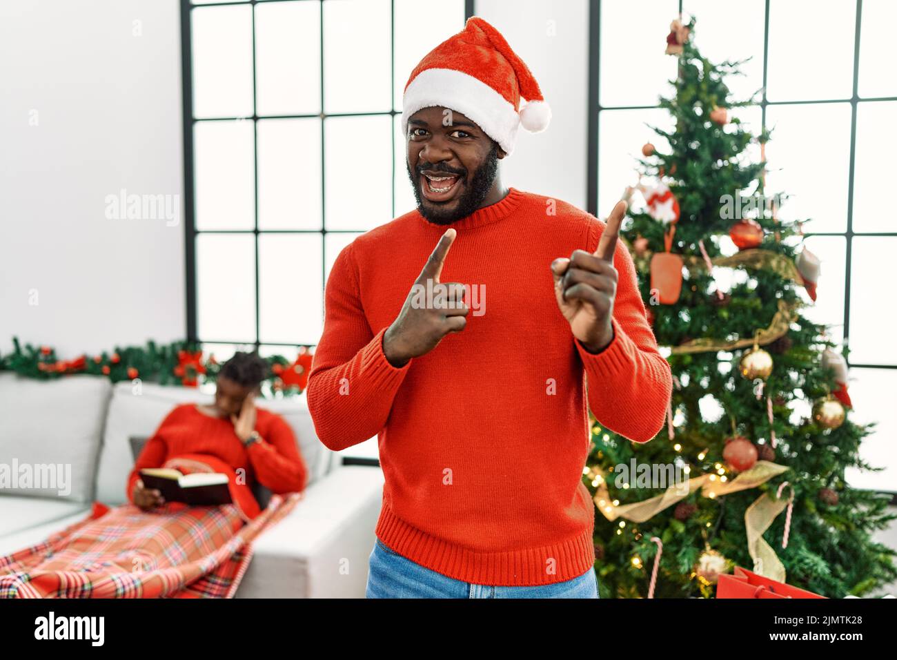 Young african american man standing by christmas tree pointing fingers ...