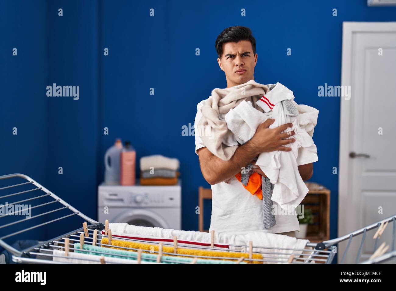 Hispanic man hanging clothes at clothesline skeptic and nervous ...