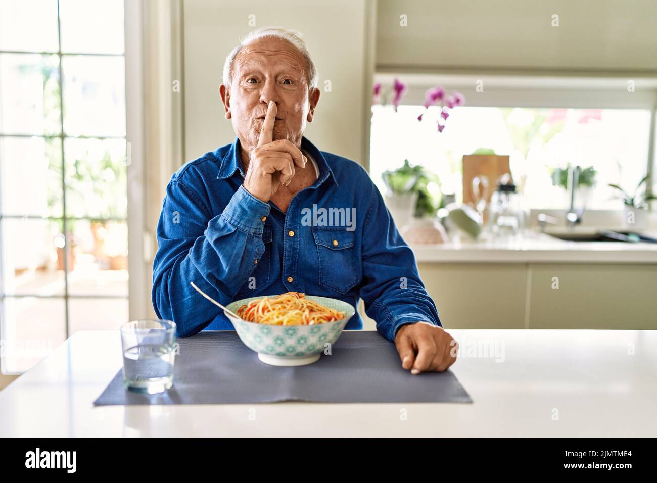 Senior man with grey hair eating pasta spaghetti at home asking to be ...