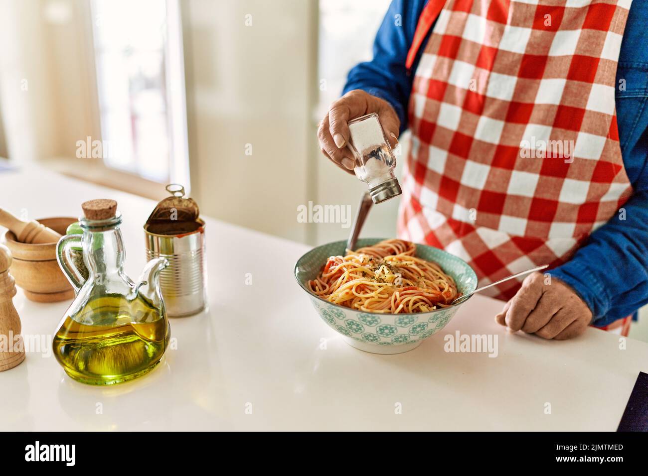 Senior man pouring salt on spaghetti at kitchen Stock Photo - Alamy