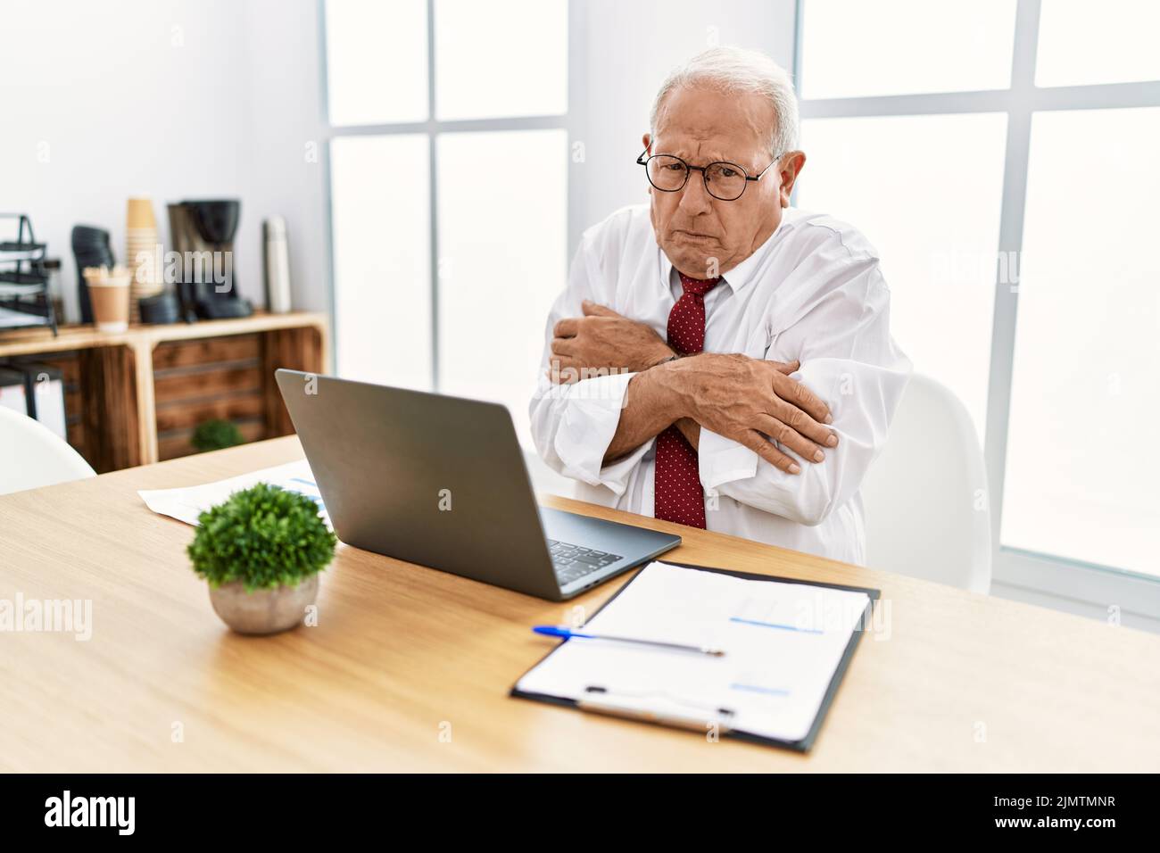 Senior man working at the office using computer laptop shaking and ...