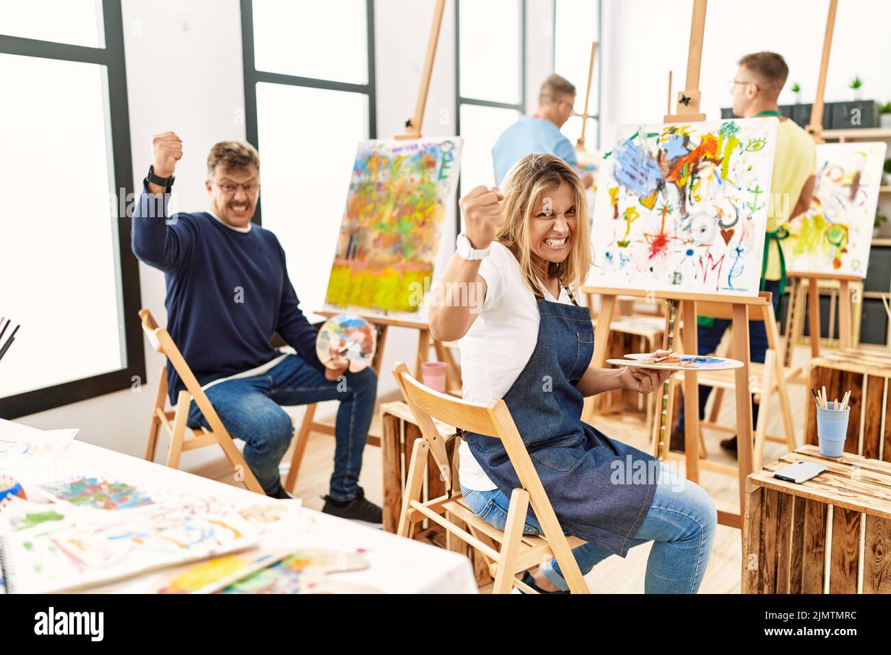 Group of middle age artist at art studio angry and mad raising fist ...