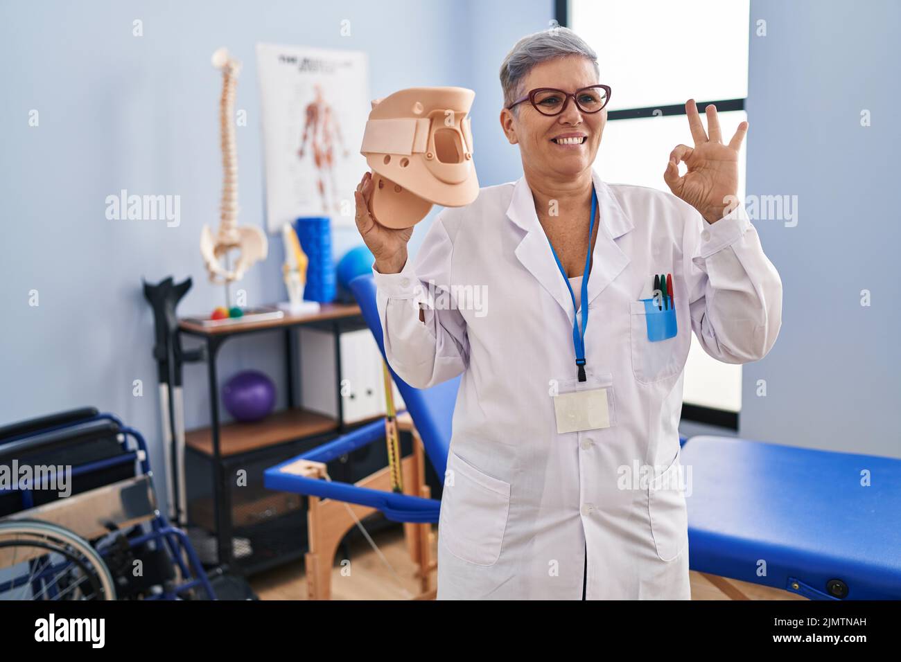 Middle age woman holding cervical neck collar doing ok sign with ...