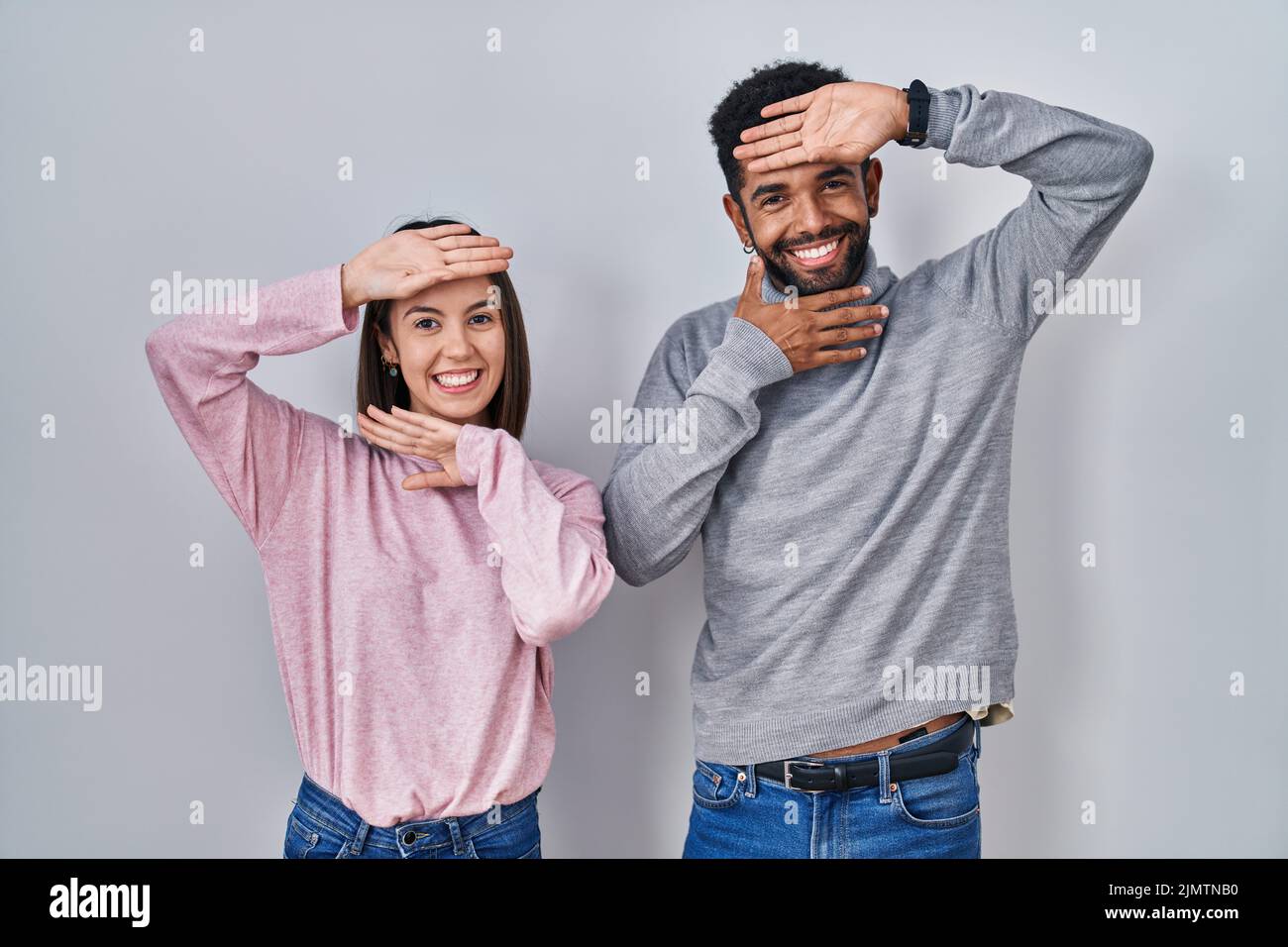Young hispanic couple standing together smiling cheerful playing peek a ...