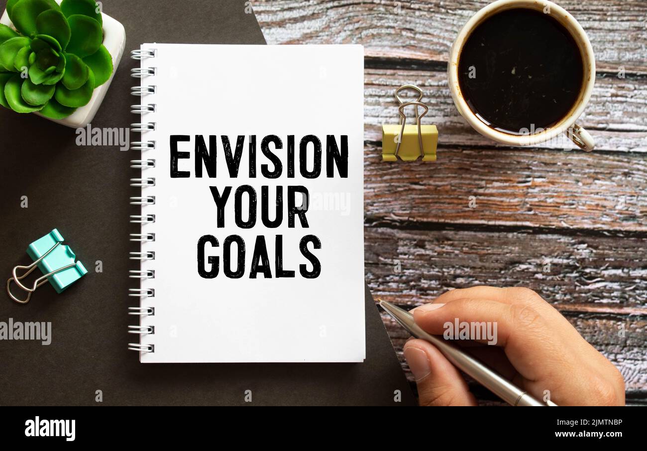 Closeup on businessman holding a card with text ENVISION YOUR GOALS ...