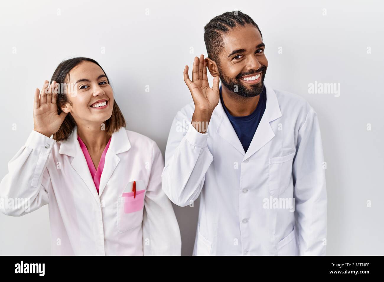 Young hispanic doctors standing over white background smiling with hand ...
