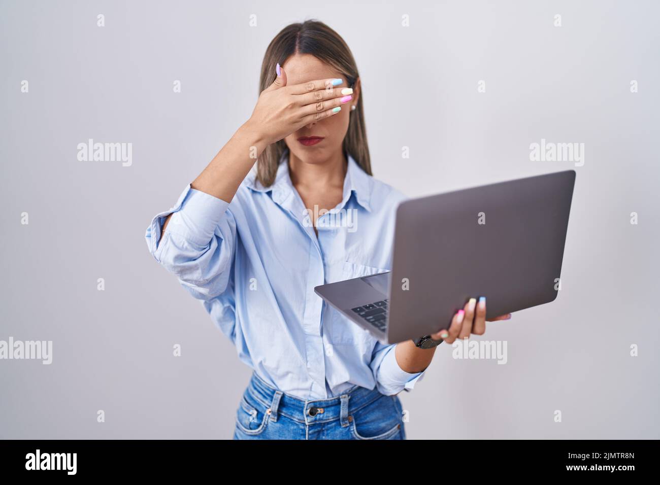 Young woman working using computer laptop covering eyes with hand ...