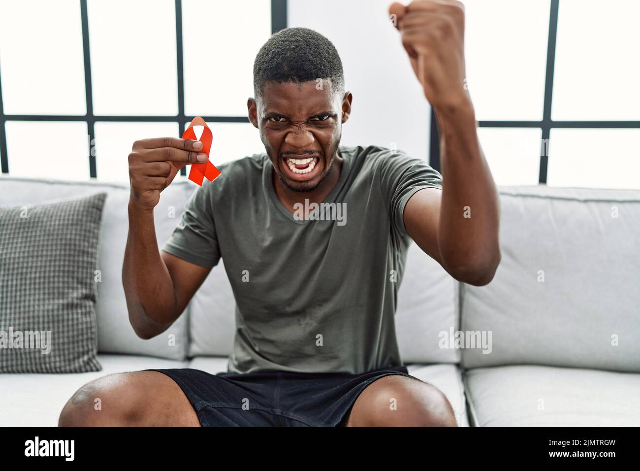 Young african american man holding support red ribbon sitting on the ...
