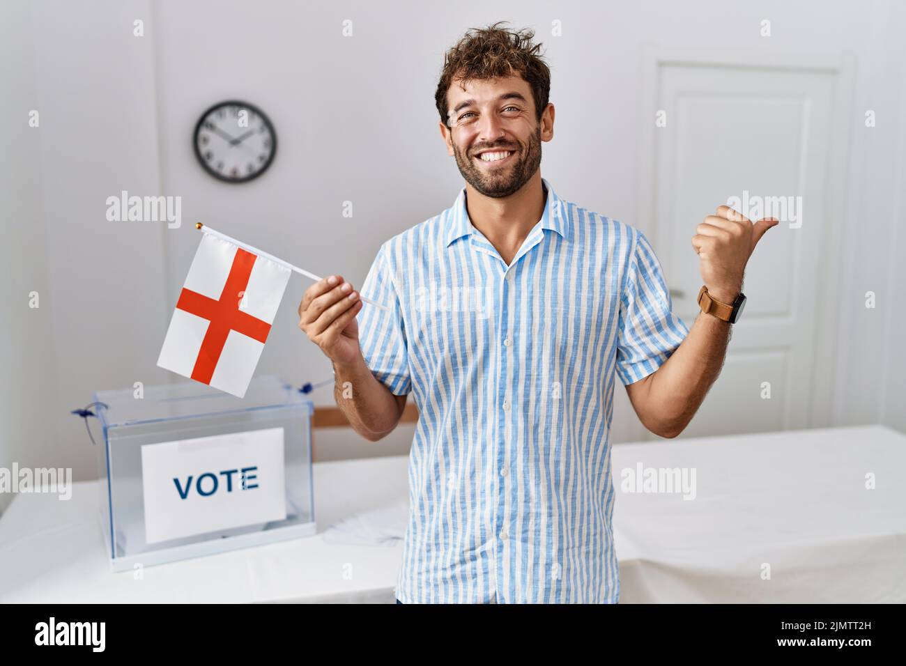 Young handsome man at political campaign election holding england flag ...