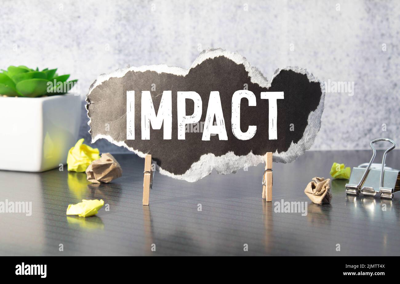 impact word written on gray background with pencils and paper clips ...