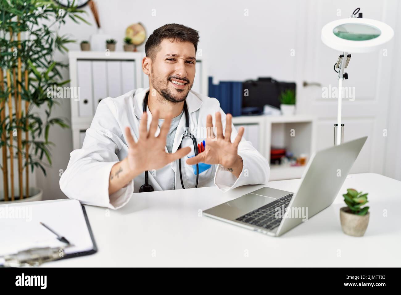 Young doctor working at the clinic using computer laptop afraid and ...