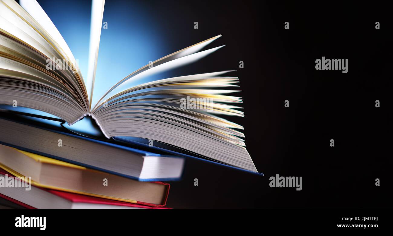 A composition with an open book lying on a stack of other books Stock ...