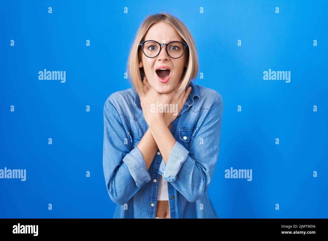 Young caucasian woman standing over blue background shouting and ...