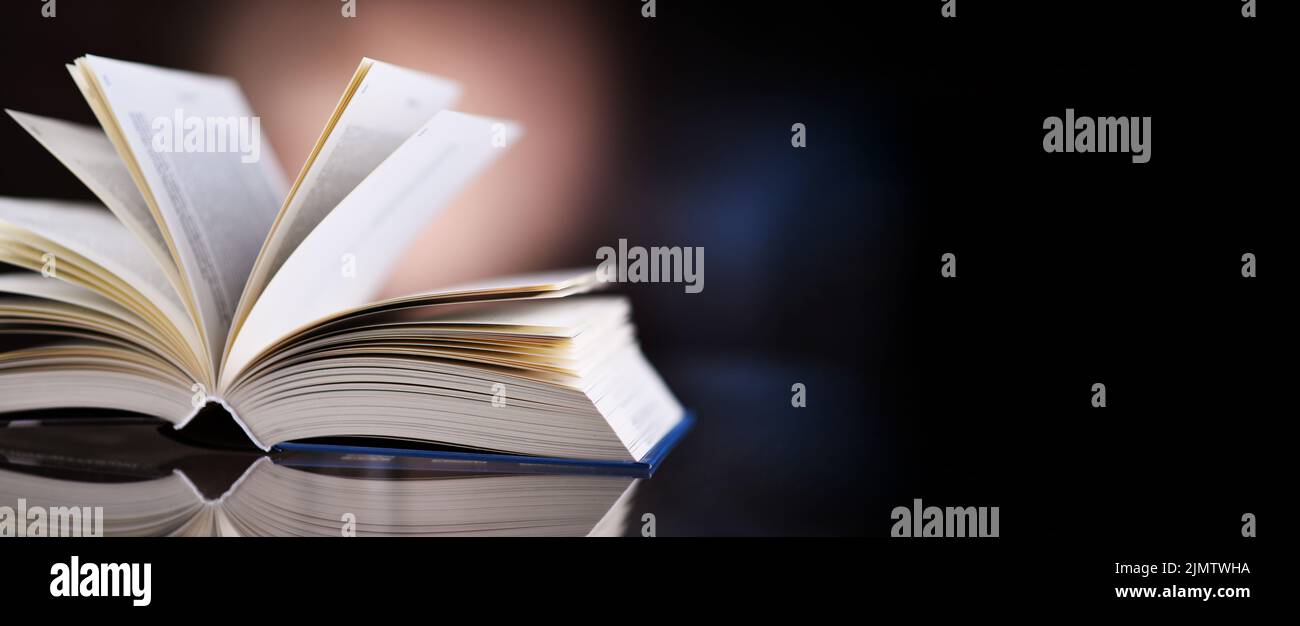 An open hardcover book lying on a table Stock Photo - Alamy