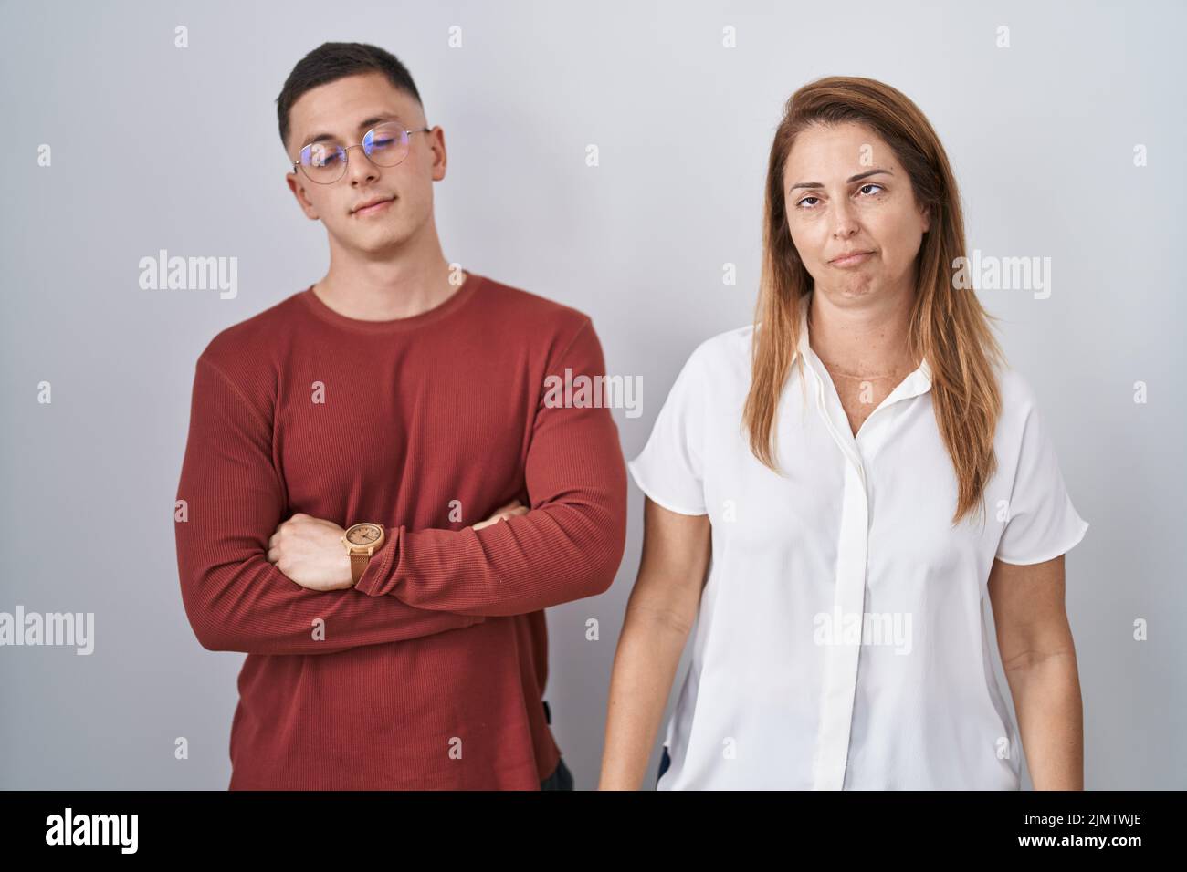 Mother and son standing together over isolated background looking ...